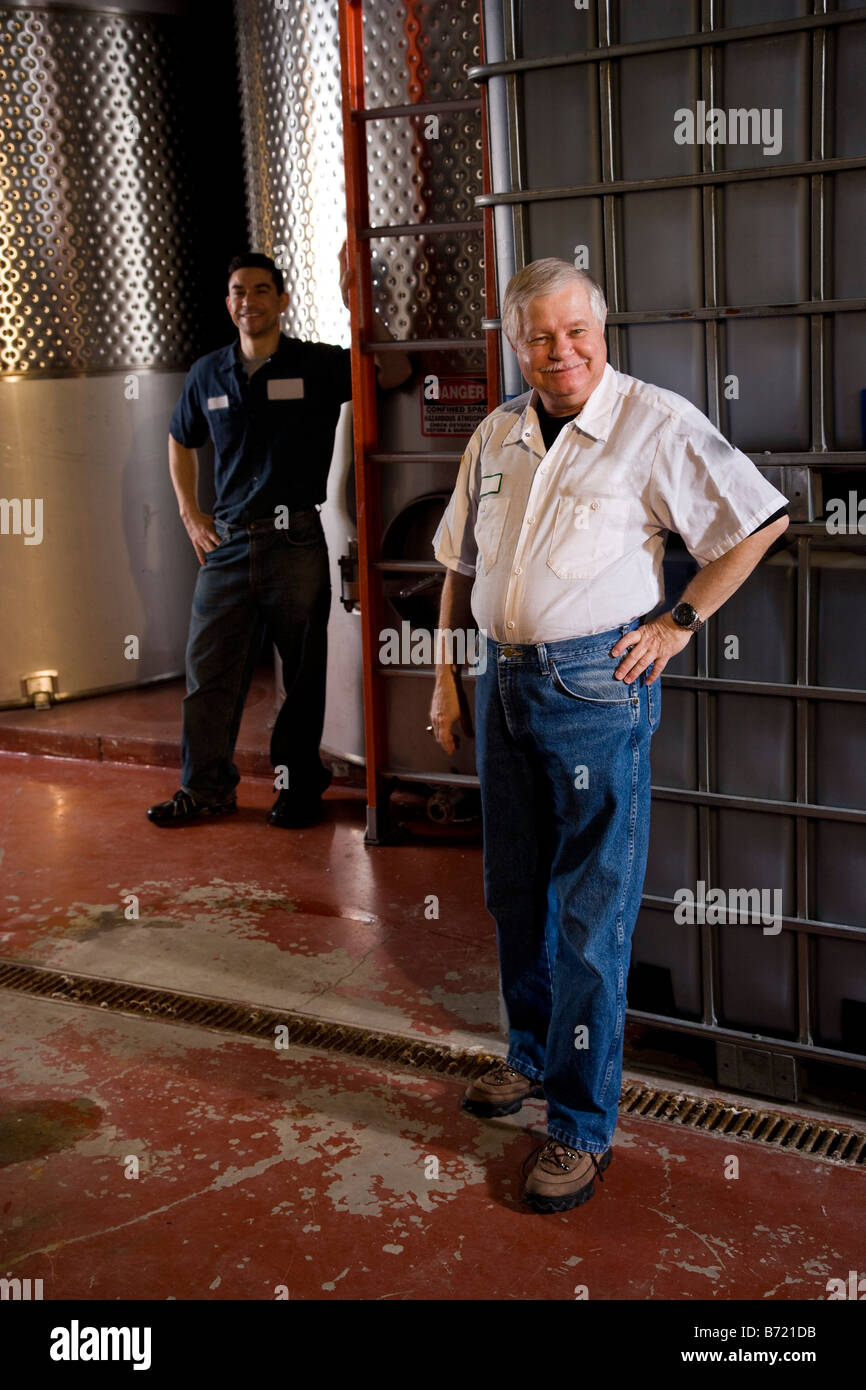 Blue-collar workers in factory posing next to storage tanks Stock Photo ...