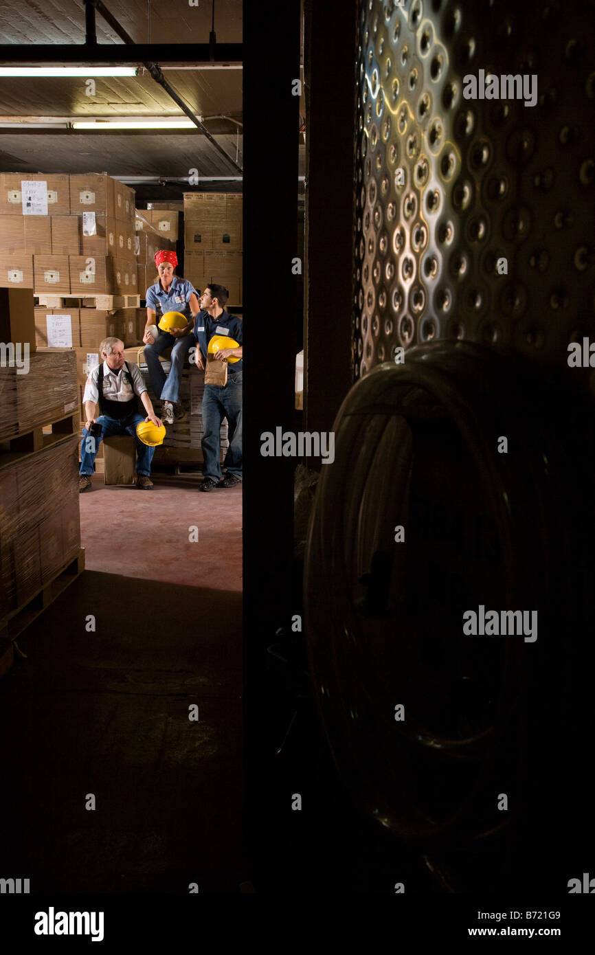 Three co-workers relaxing in storage warehouse Stock Photo - Alamy