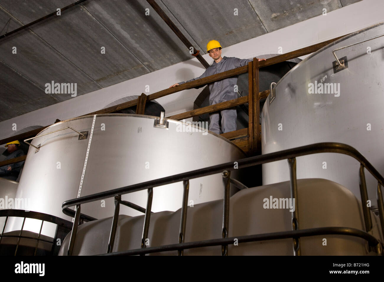 Blue-collar workers in factory overlooking storage tanks Stock Photo ...