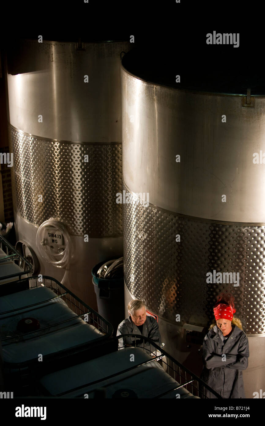 Blue-collar workers in factory next to storage tanks Stock Photo - Alamy