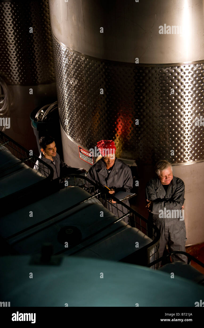 Blue-collar workers in factory next to storage tanks Stock Photo - Alamy