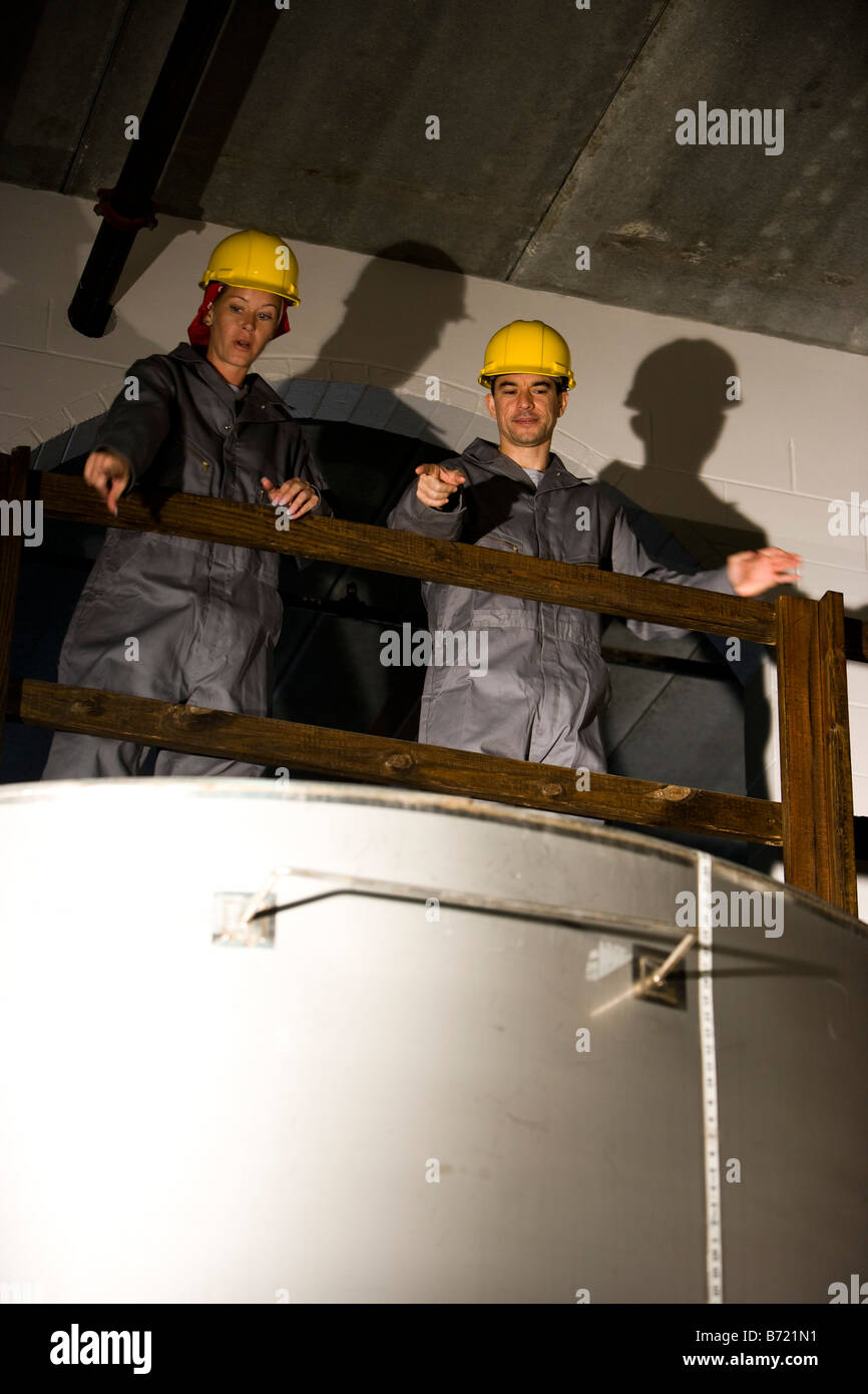 Two workers overlooking storage tank Stock Photo - Alamy