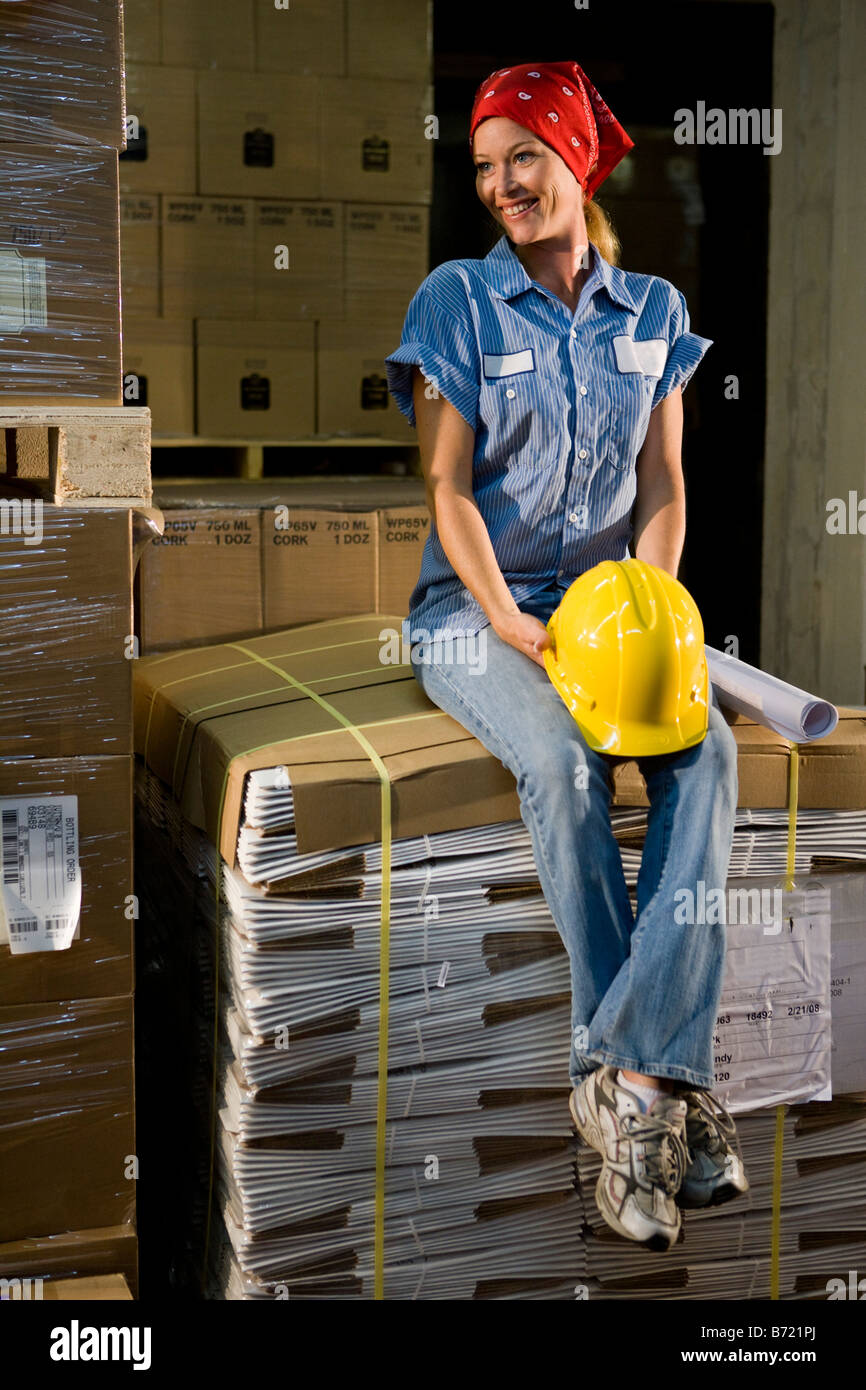 Female worker sitting on cardboard boxes in storage warehouse Stock ...