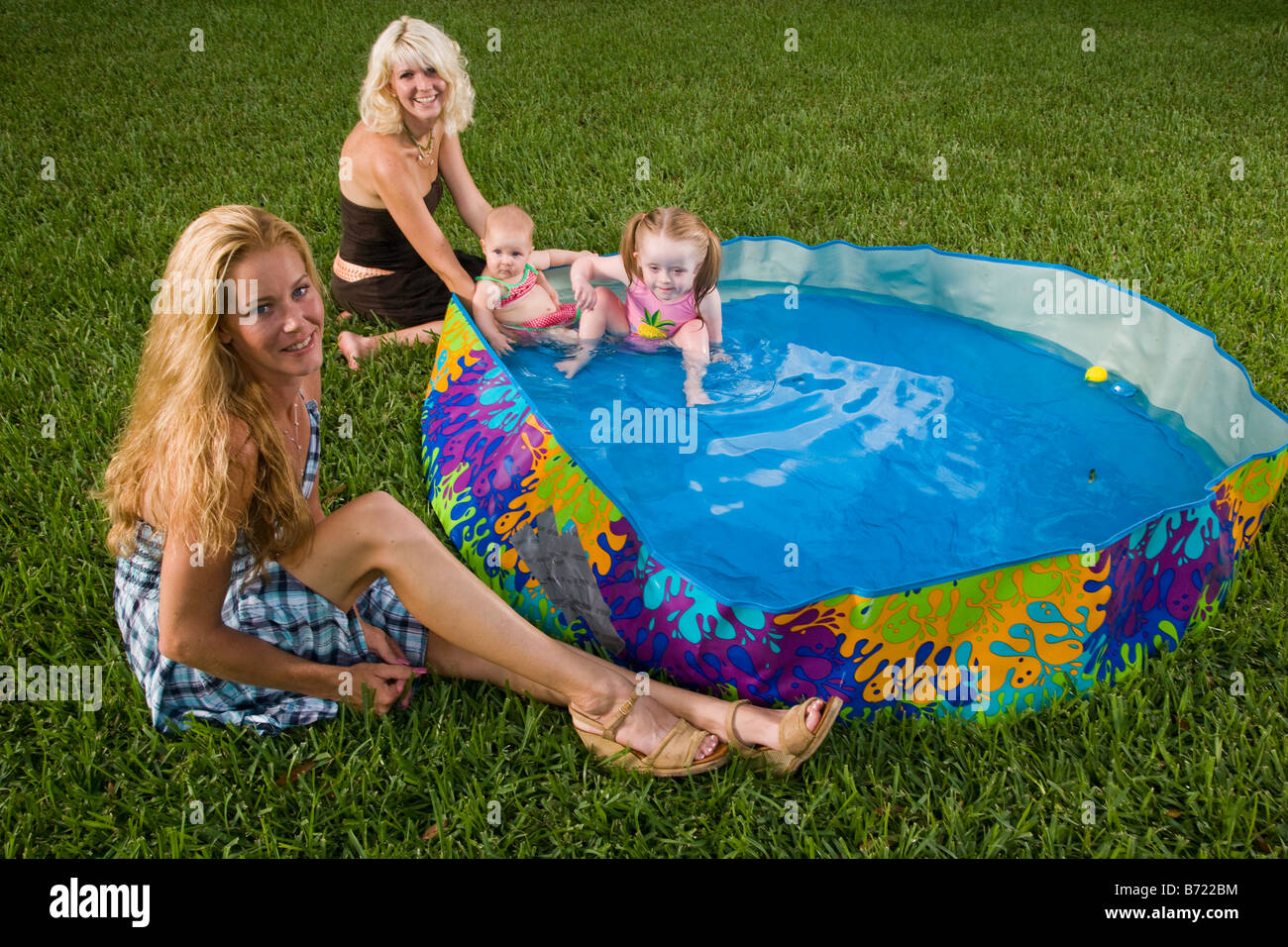 Young women with baby and girl in kiddie pool sitting in backyard Stock ...