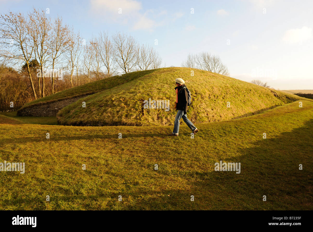 A walker passes the Stone Age long barrow of Belas Knapp near ...