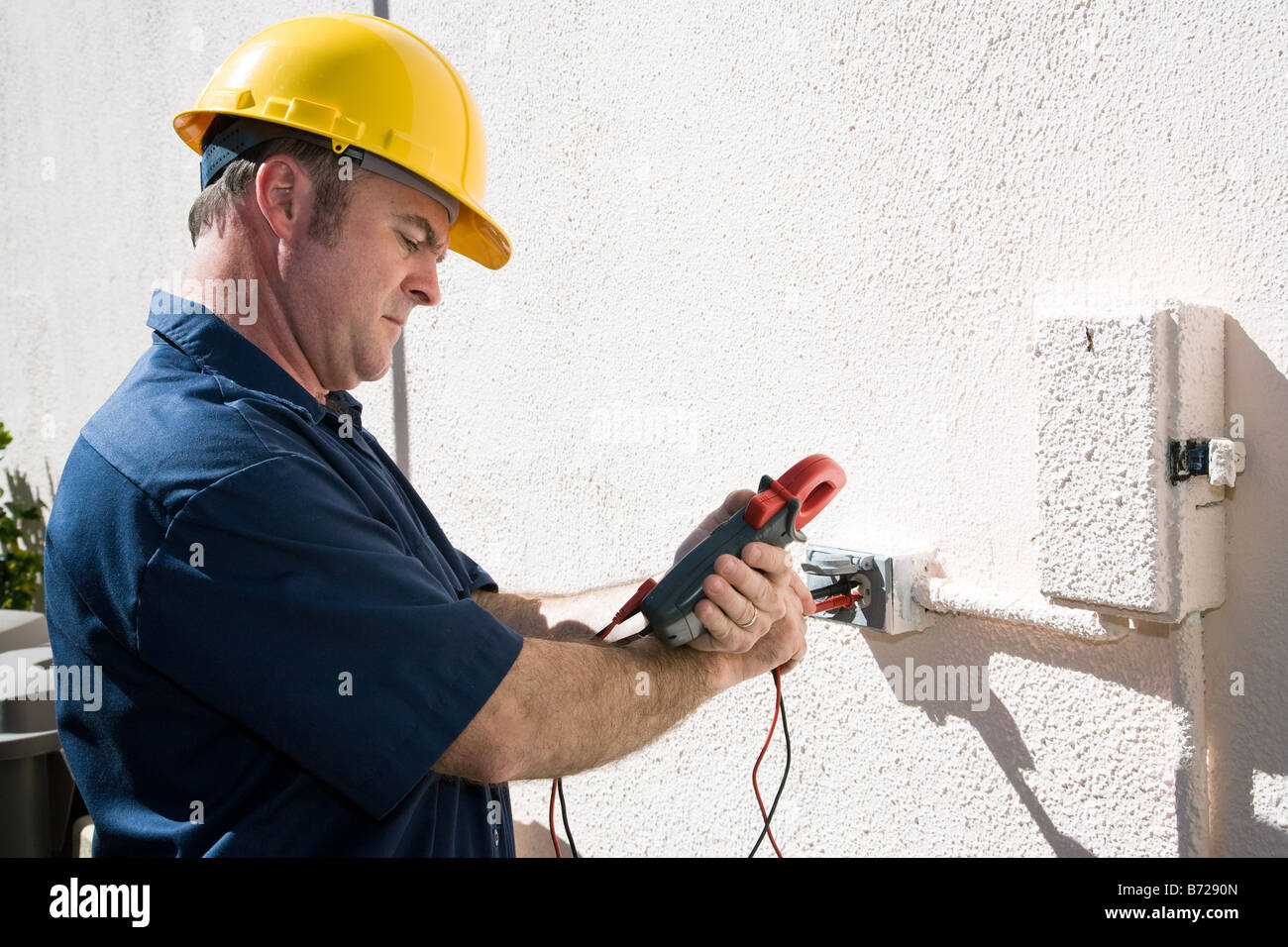 Electrician using a meter to check the voltage on an outdoor receptacle ...
