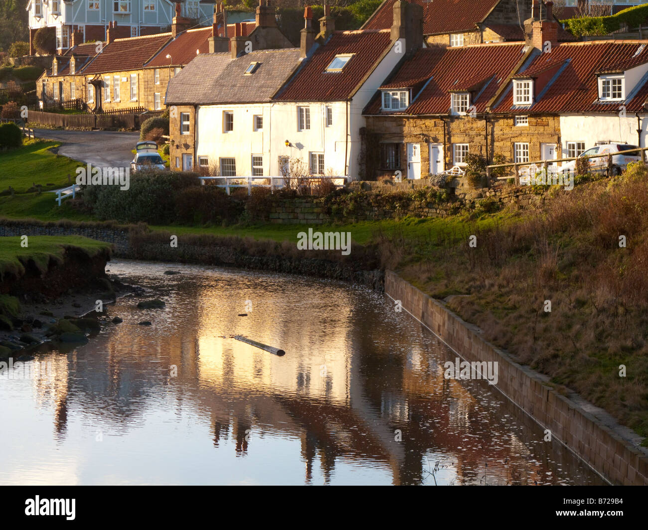 Cottages reflecting over a slow running bend in stream Stock Photo - Alamy
