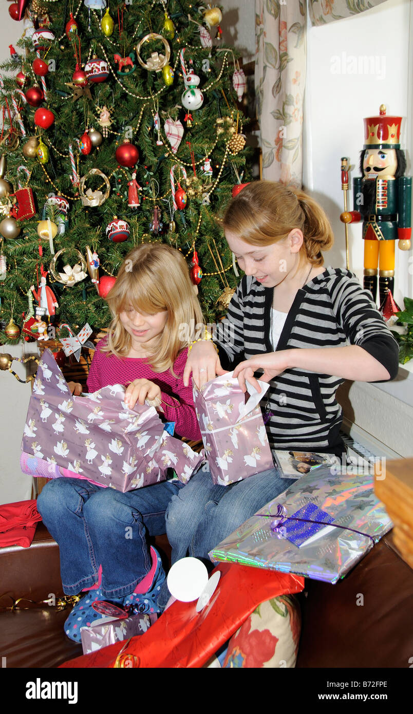 A decorated Christmas tree and two girls opening their xmas presents ...