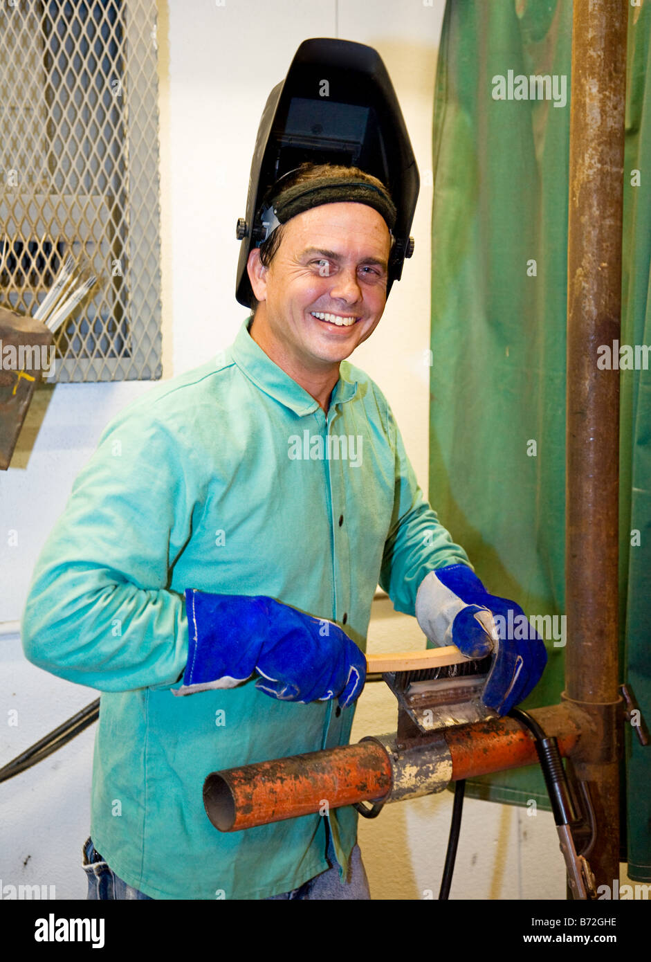 Friendly smiling welder brushing metal filings off his latest project ...