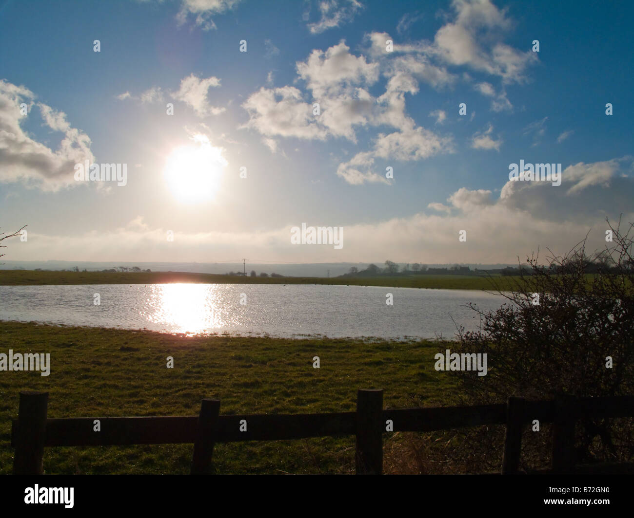 Reflective sun on water over countryside Stock Photo - Alamy