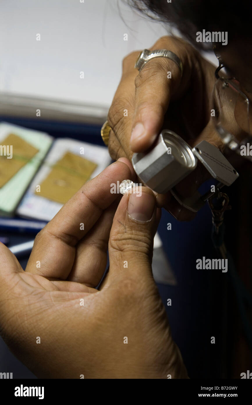 Diamond worker looks through a magnifying lens at a diamond he is ...