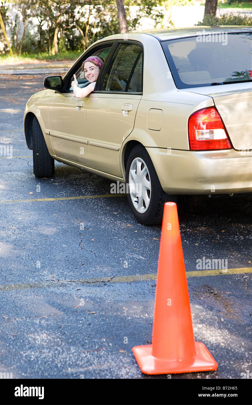 Teen girl taking her driving test leans out the window to give an ...