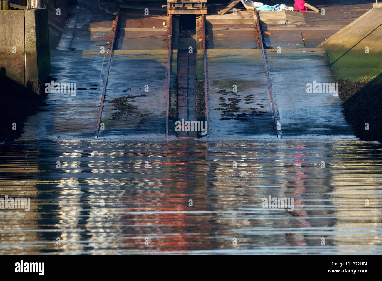 boat slipway leading to water with reflection in harbour county down ...