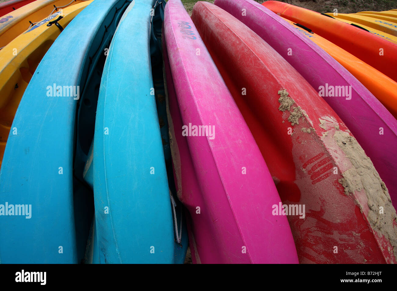 A ROW OF BRIGHTLY COLOURED CANOES ON A BEACH QUEENSLAND AUSTRALIA ...