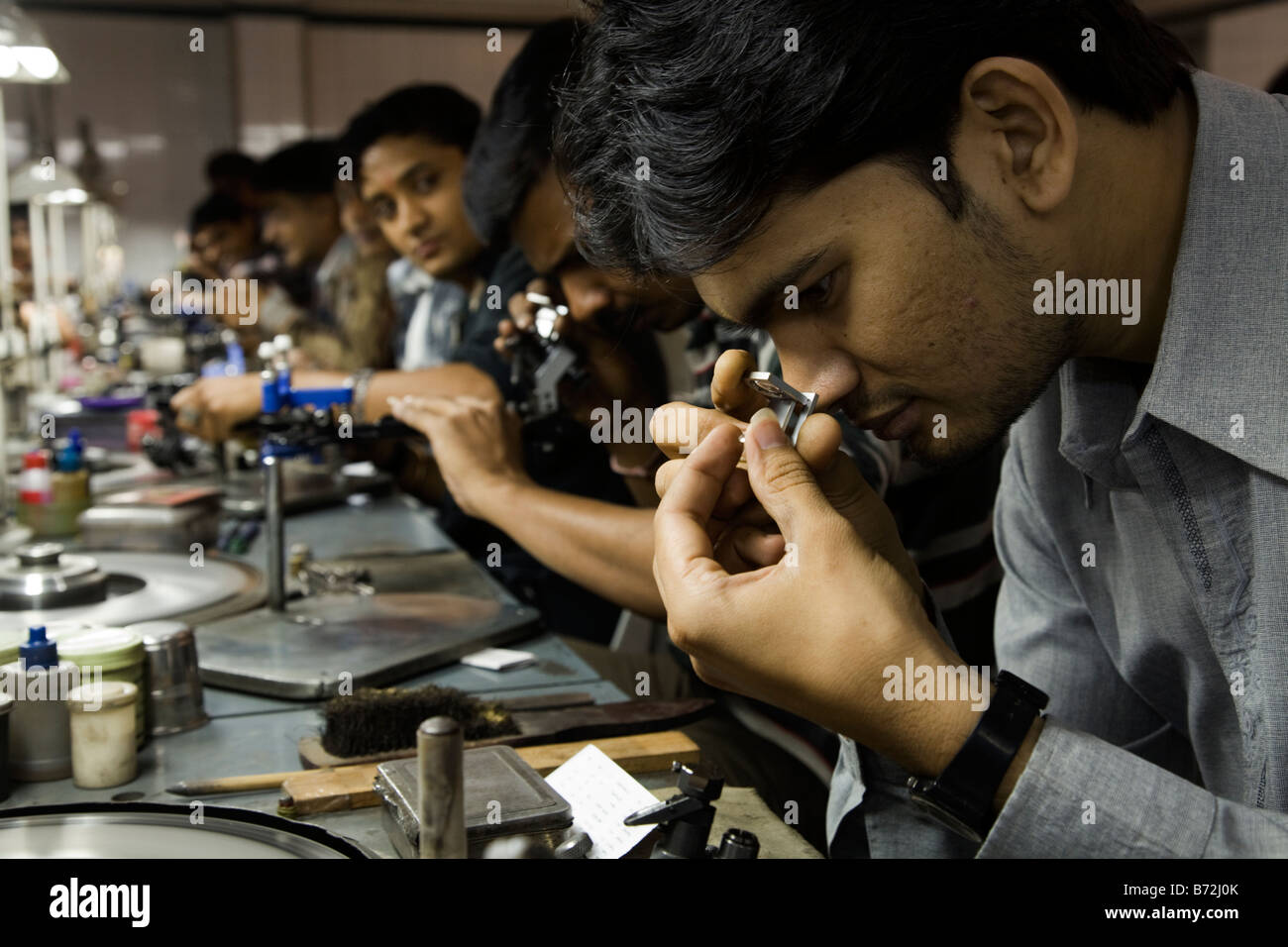 Diamond worker looks through a magnifying lens at a diamond he is ...