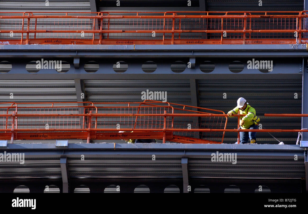 A construction worker puts up safety fencing on an office block under ...