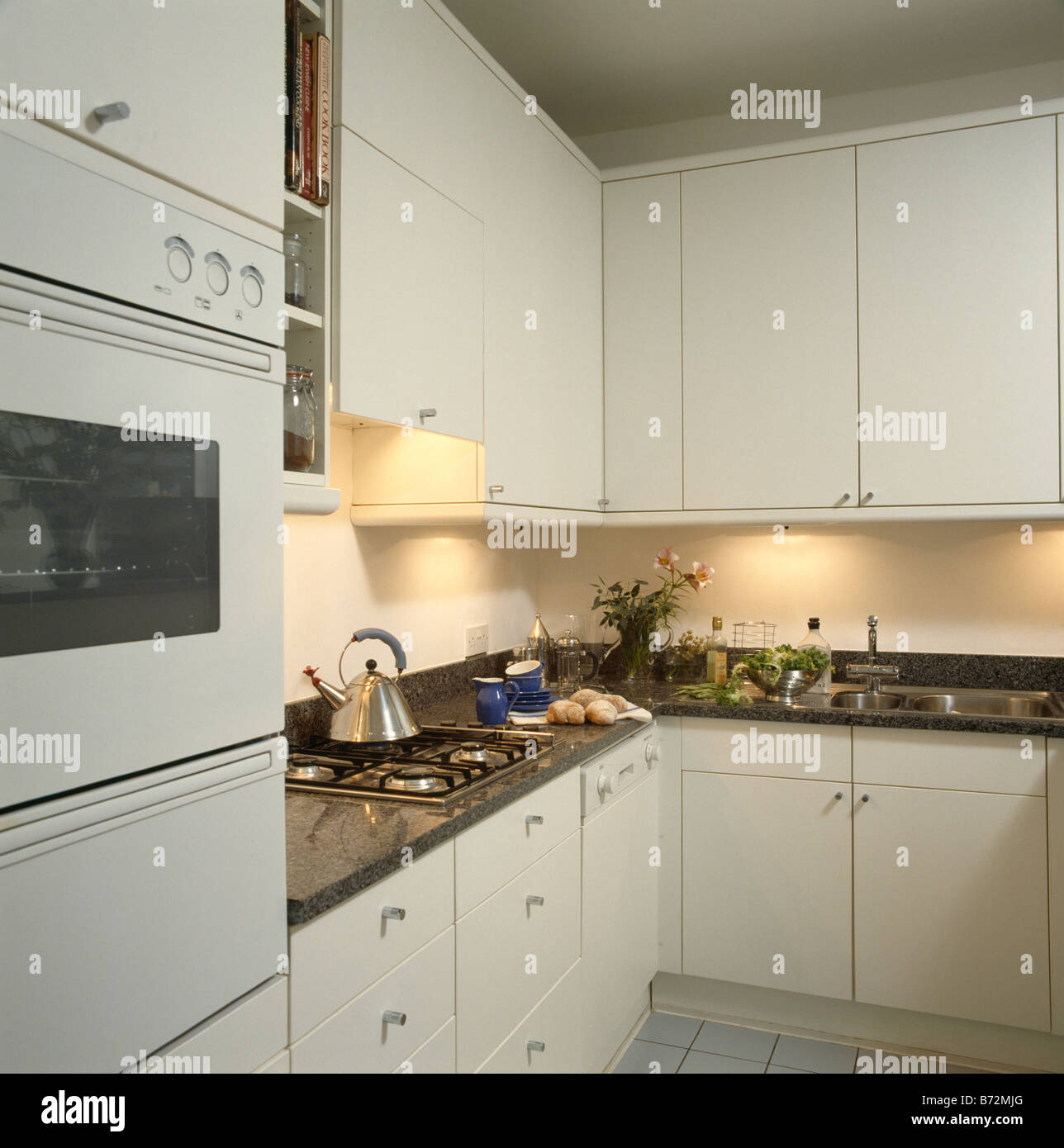 Alessi kettle on hob fitted into granite worktop below fitted cupboards ...