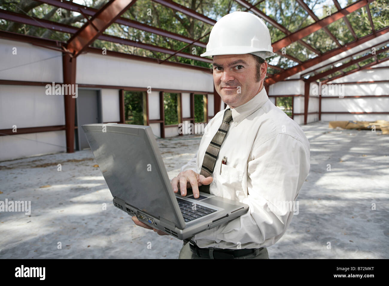 A construction inspector or engineer using his laptop on the job site ...