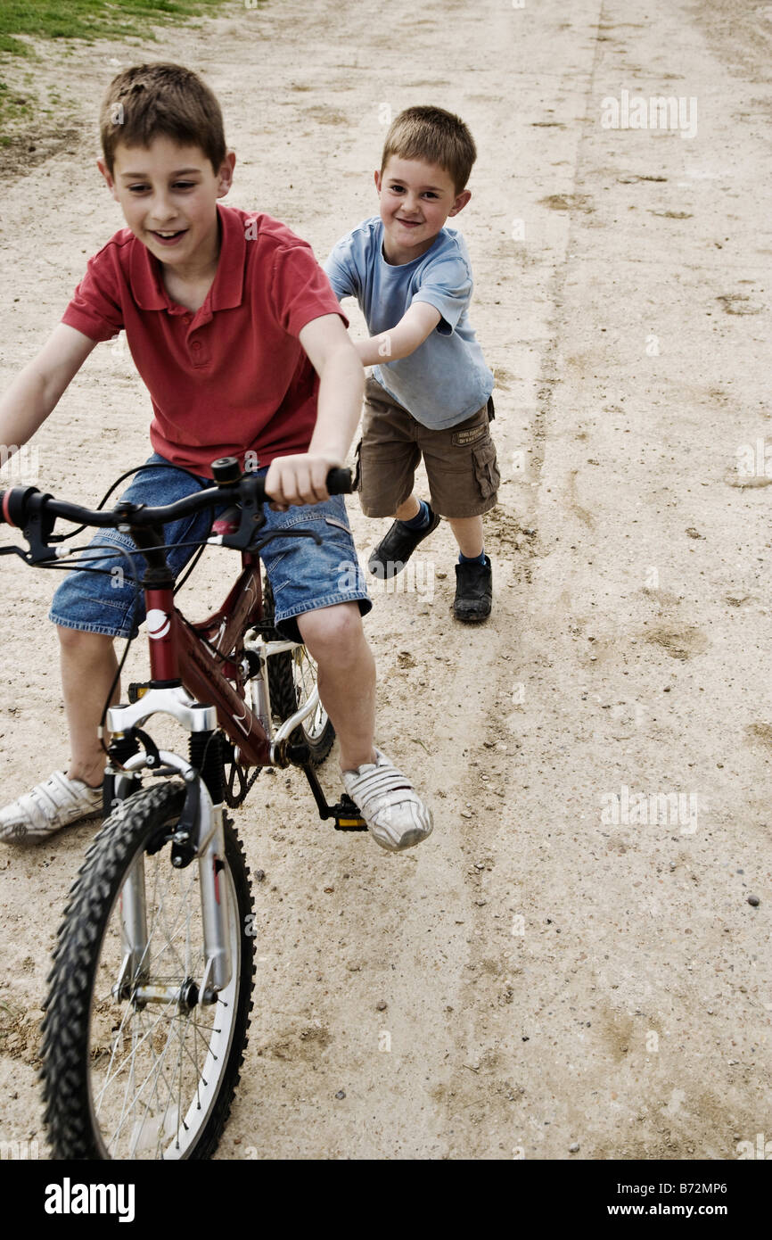 Two boys playing on a bicycle Stock Photo - Alamy