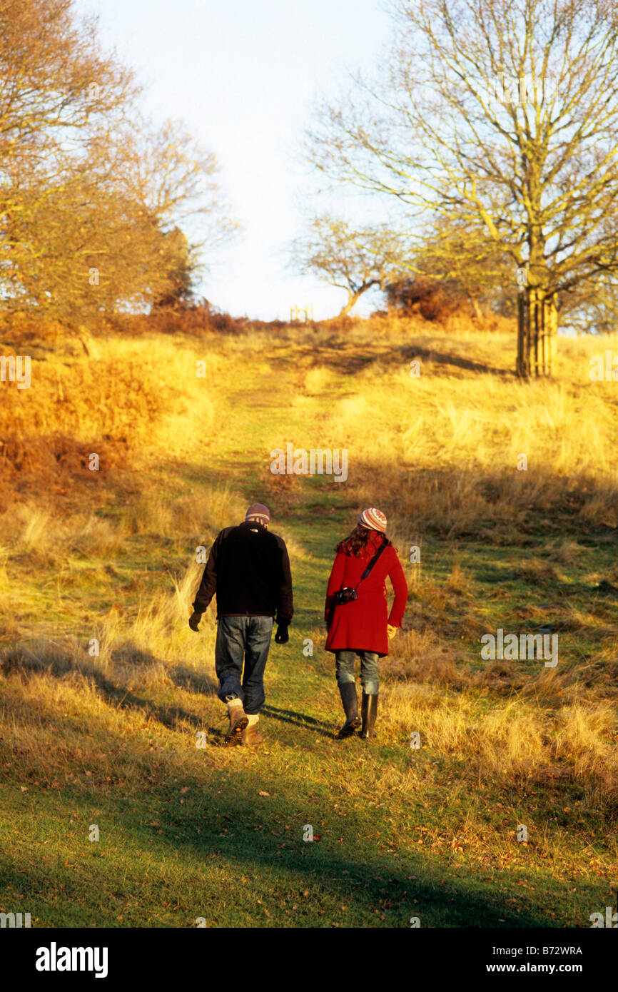 Couple walking through winter light in Richmond Park Stock Photo - Alamy