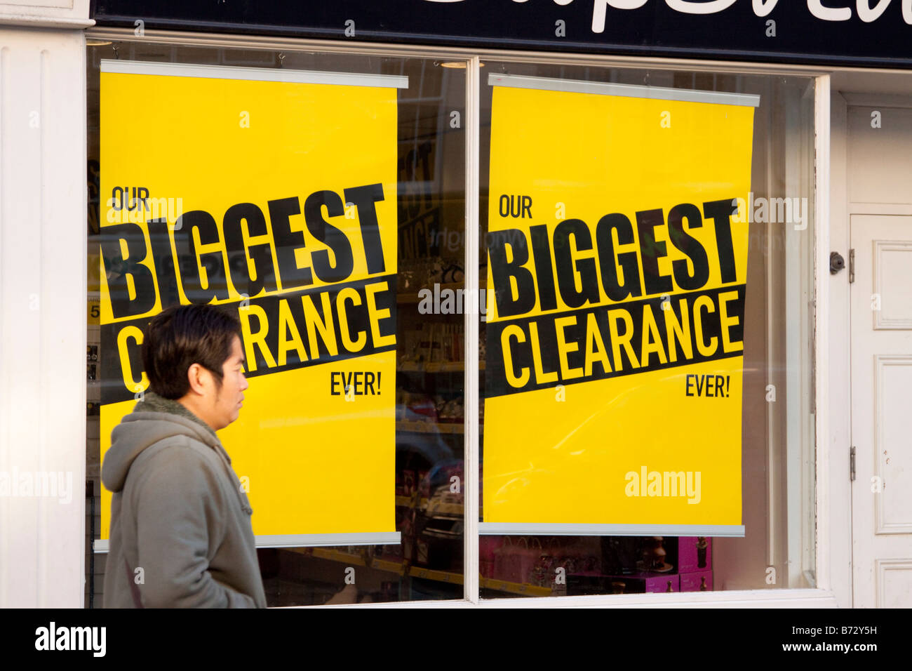 2 YELLOW SALE SIGNS IN A SHOP WINDOW CLAIMING THE BIGGEST CLEARANCE ...