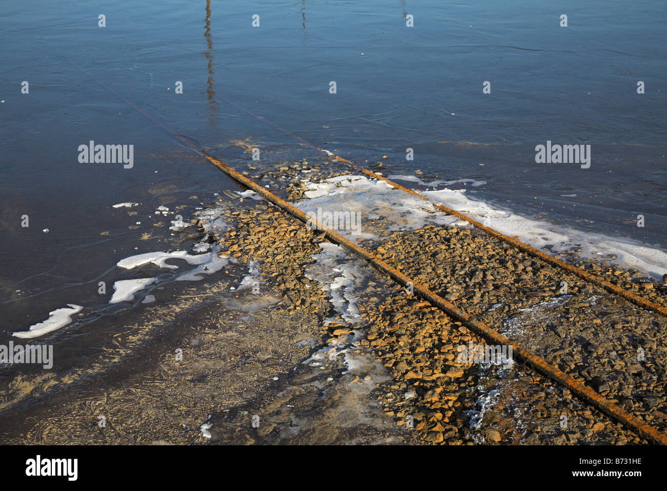 Old and disused railway track entering water Stock Photo - Alamy