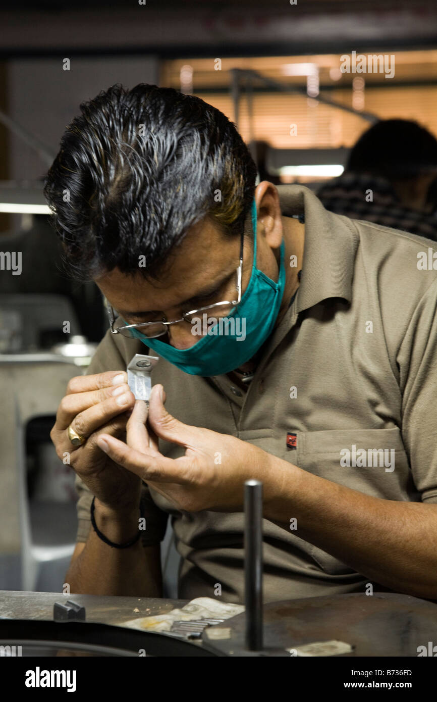 Diamond worker looking at a diamond he is polishing, and breathing ...