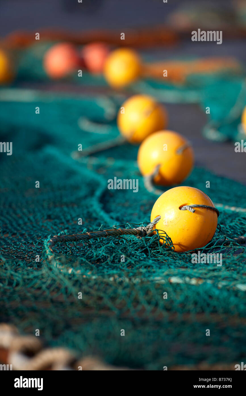 fishing net with yellow floats lying out on the quay to dry in the sun ...