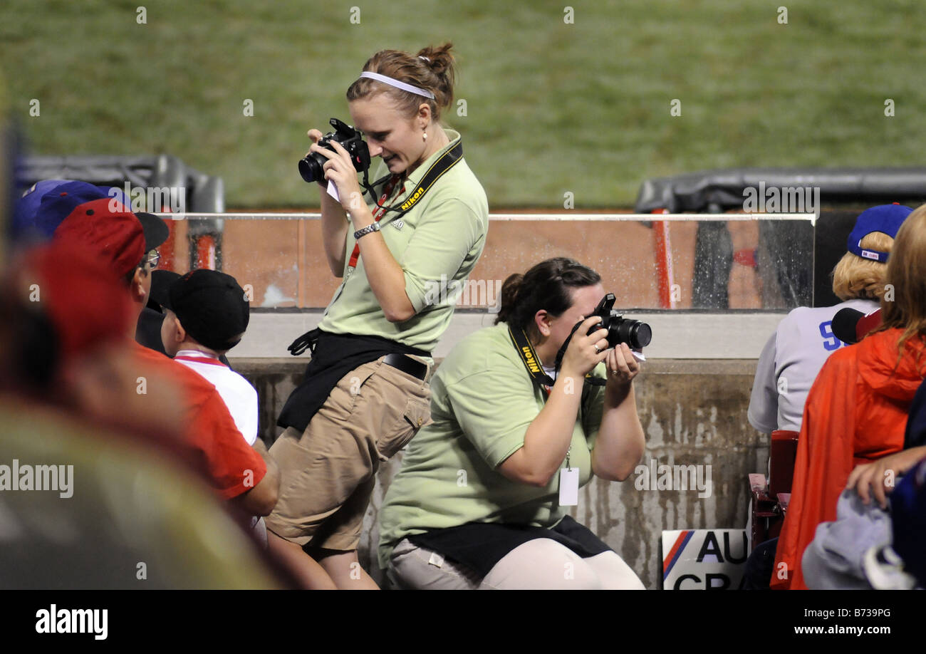 Two young photographers photograph sports fans in their seats at a ...