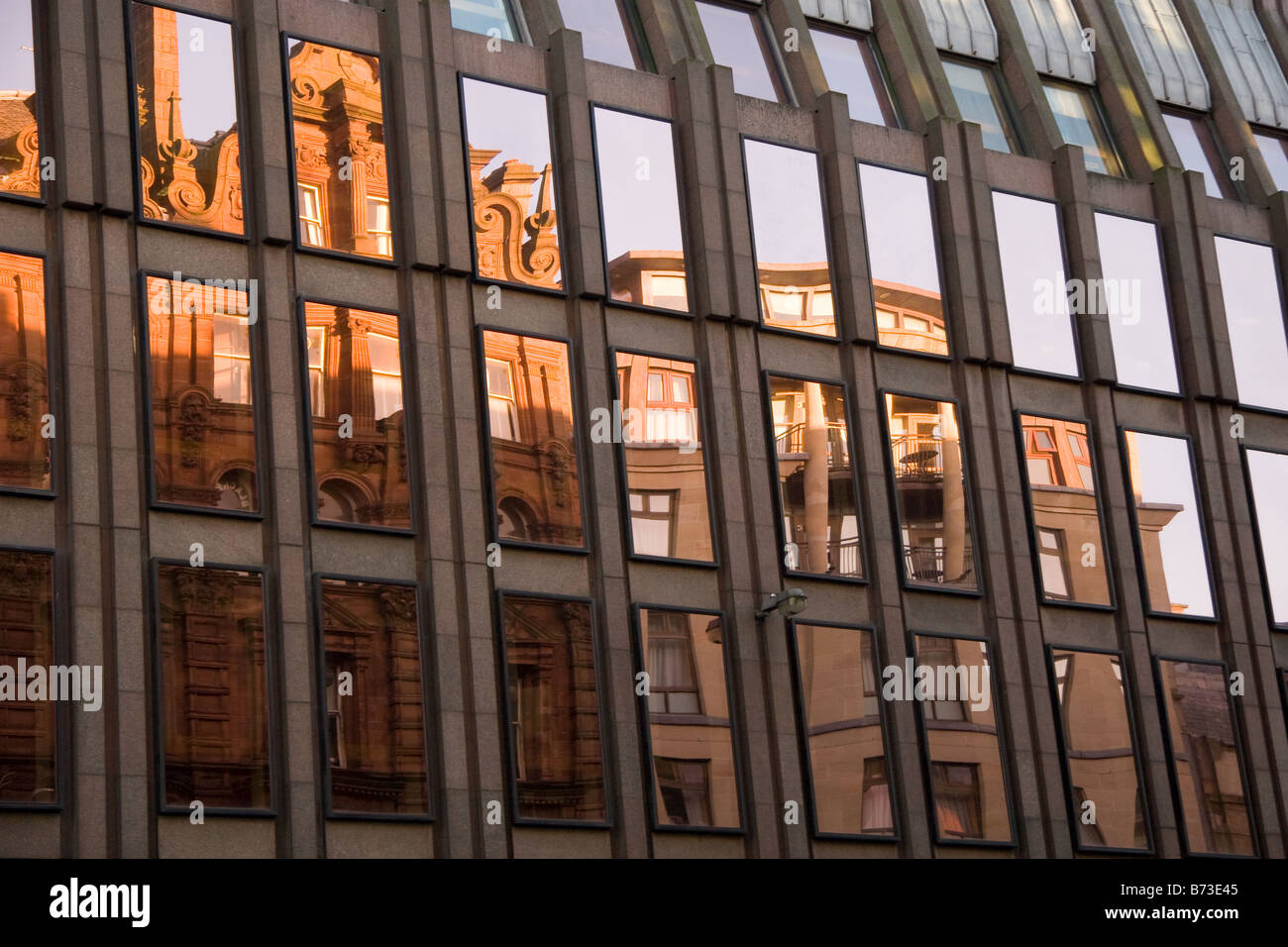 An old building reflecting in the mirrored glass of a new building ...
