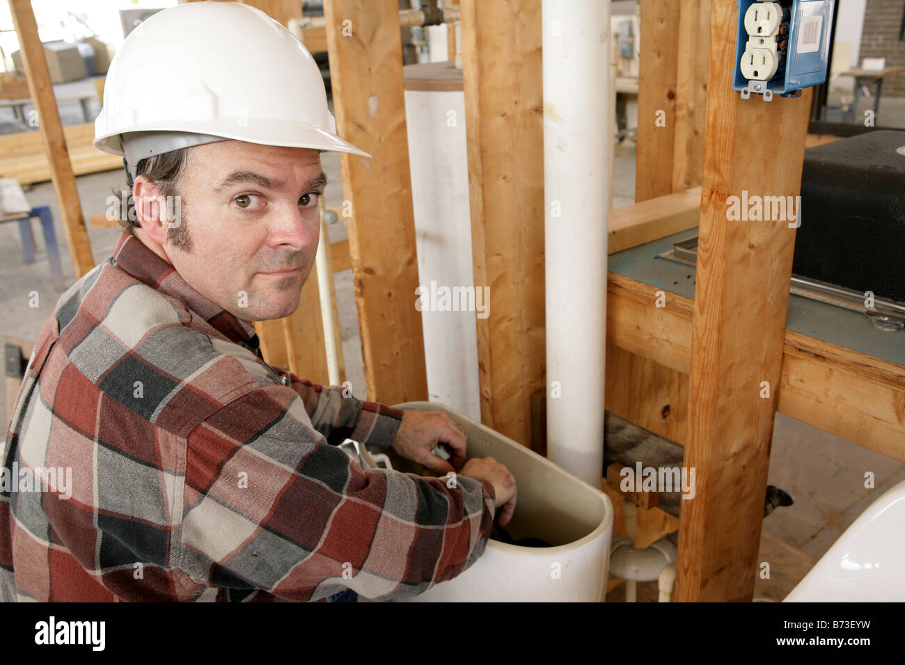 A construction plumber fixing a toilet on new building construction ...