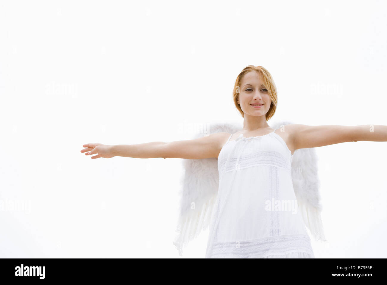Young woman wearing angel wings smiling portrait Stock Photo - Alamy