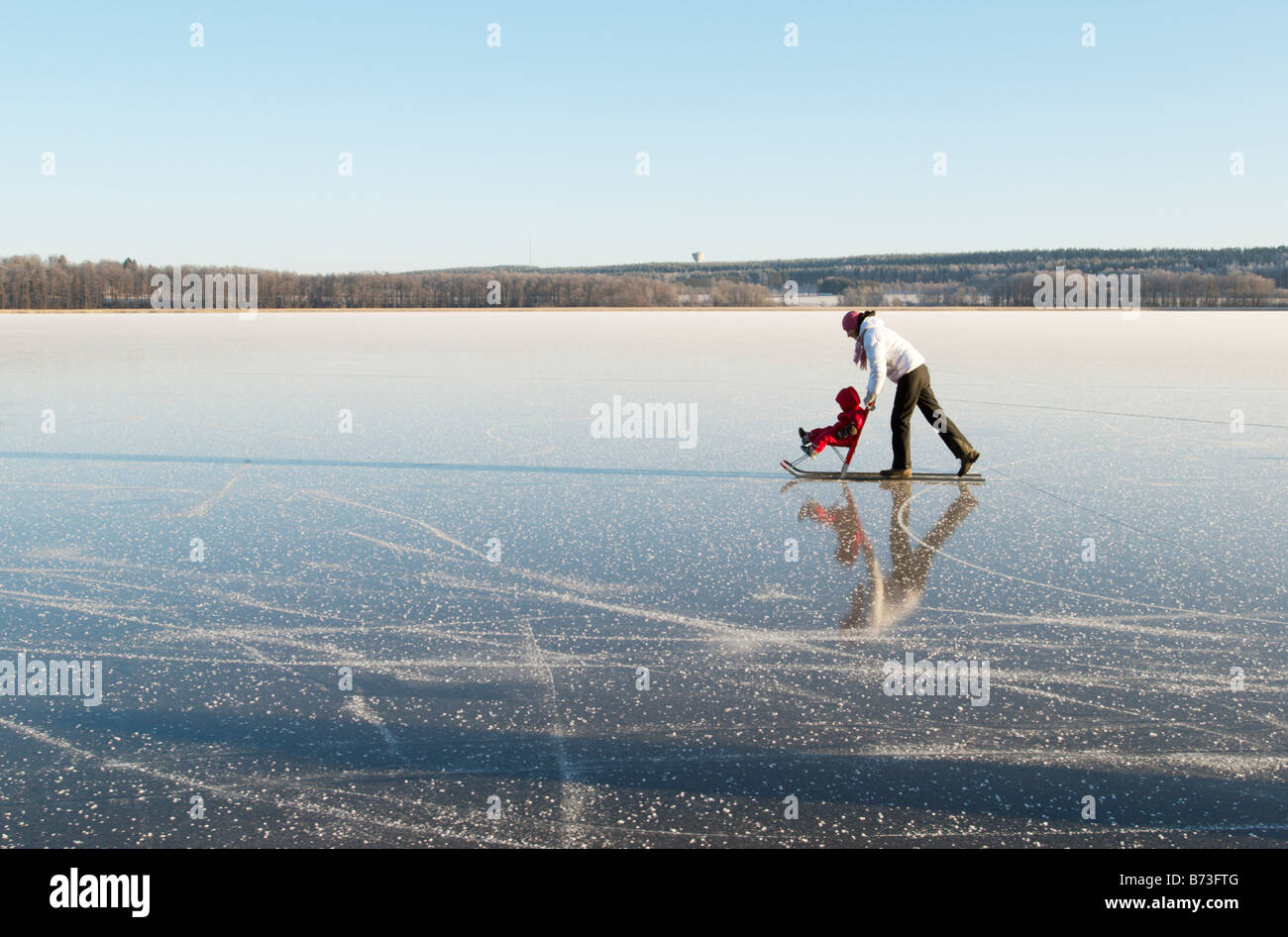 Mother and child having fun on lake ice with a traditional nordic ...