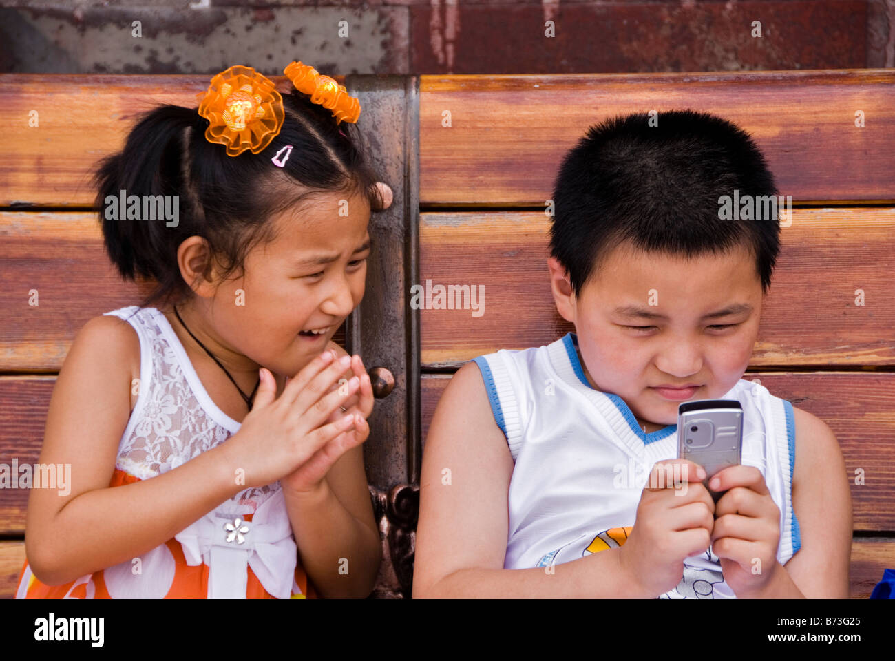 Boy playing with mobile phone while girl watching Forbidden city ...