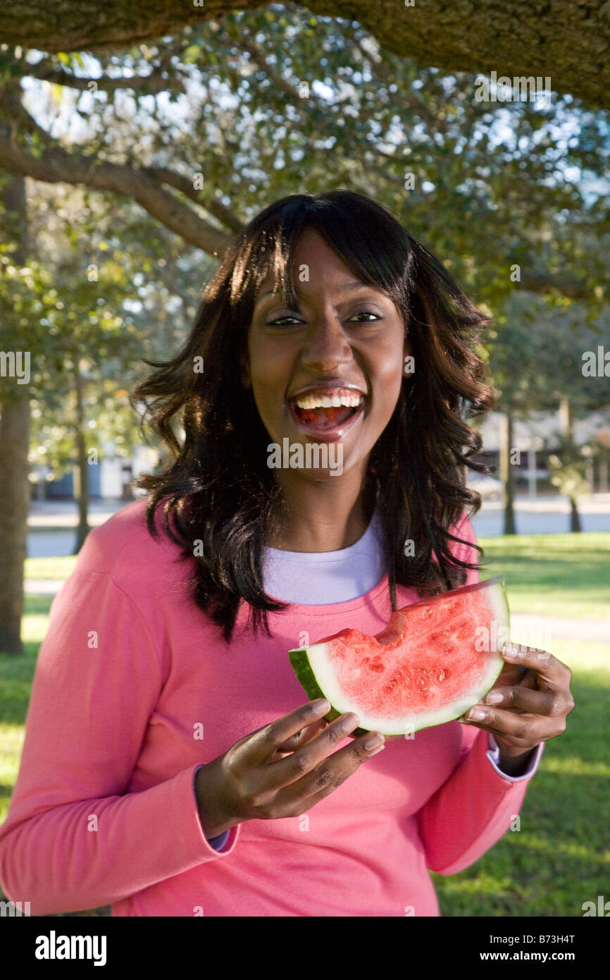 Young African American woman eating watermelon in park Stock Photo - Alamy