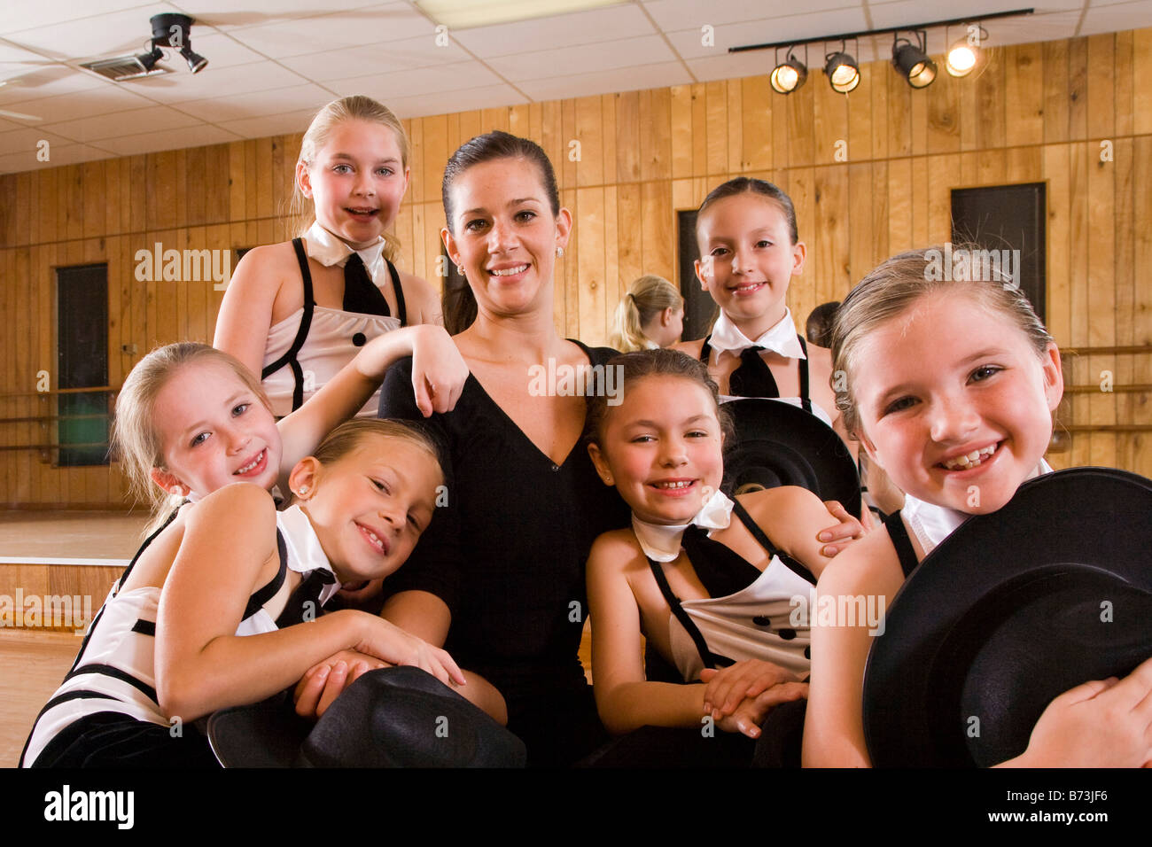 Girls in costume posing with teacher in dance studio Stock Photo - Alamy