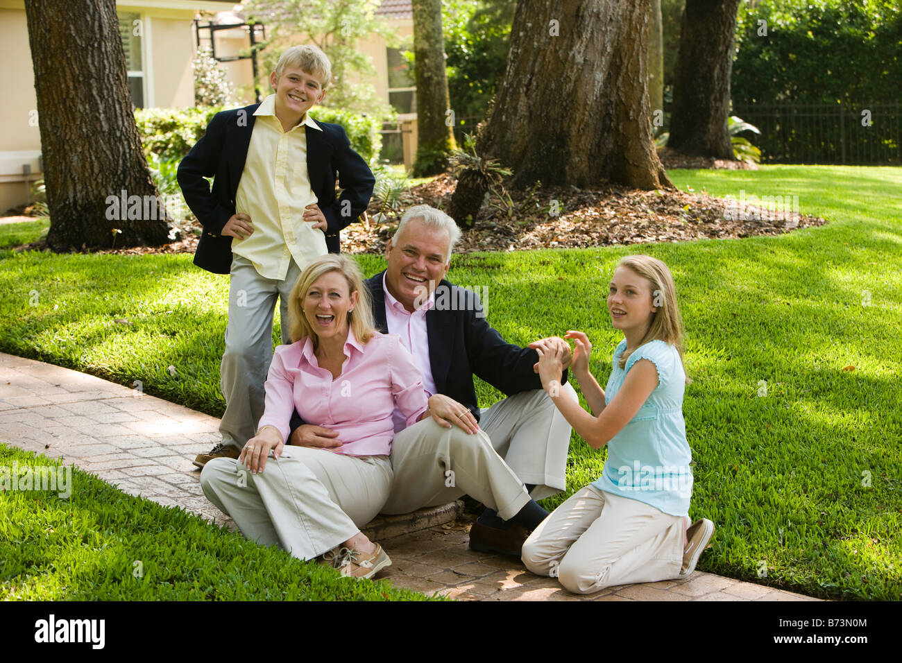 Family of four sitting together outdoors dressed in Sunday clothes ...