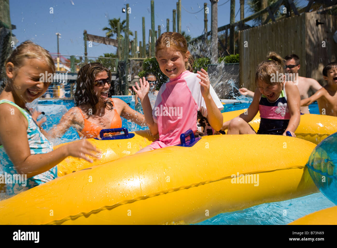 Three young girls splashing on raft at a water pak Stock Photo - Alamy