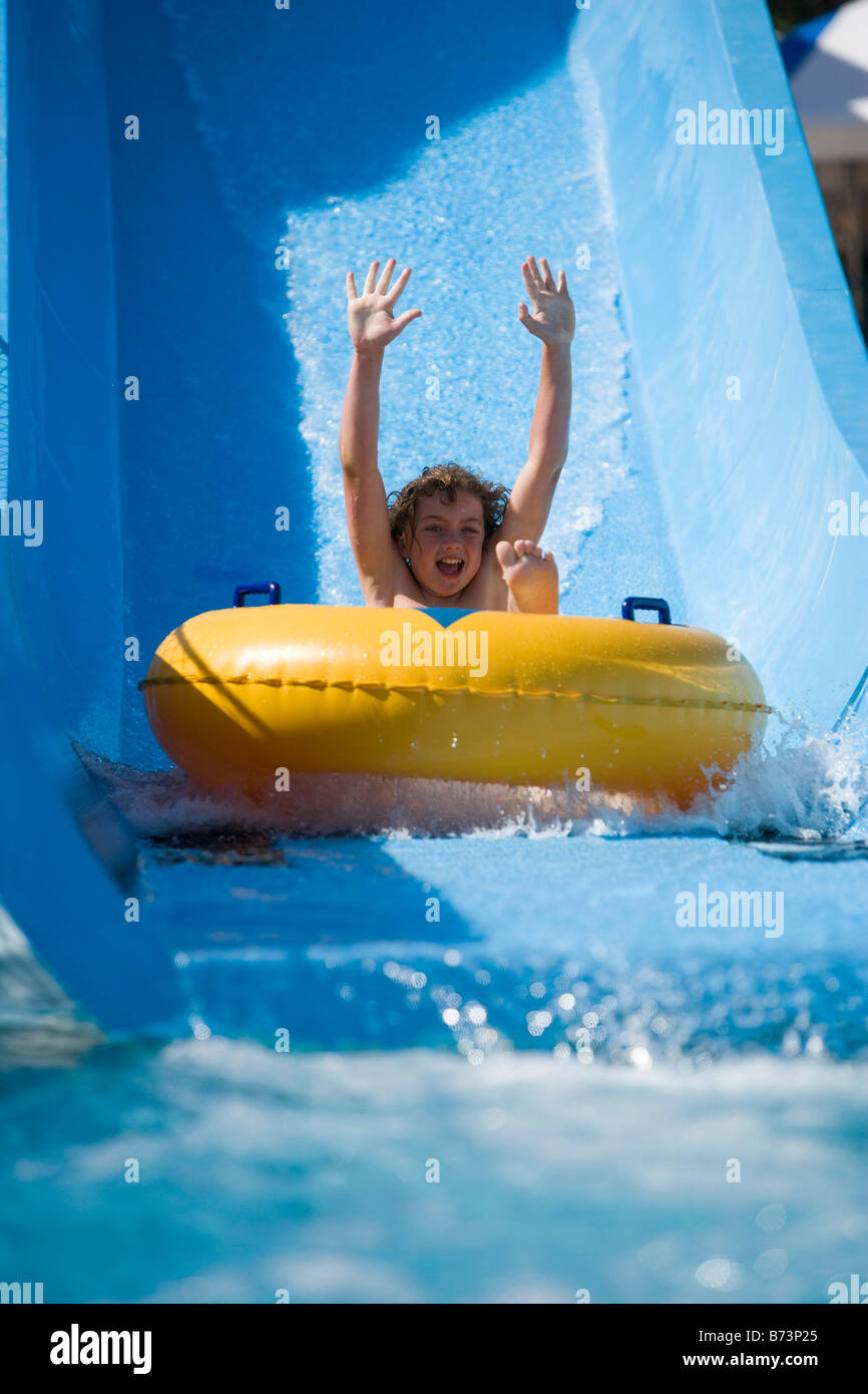Young boy sliding down water slide on innertube in water park Stock ...