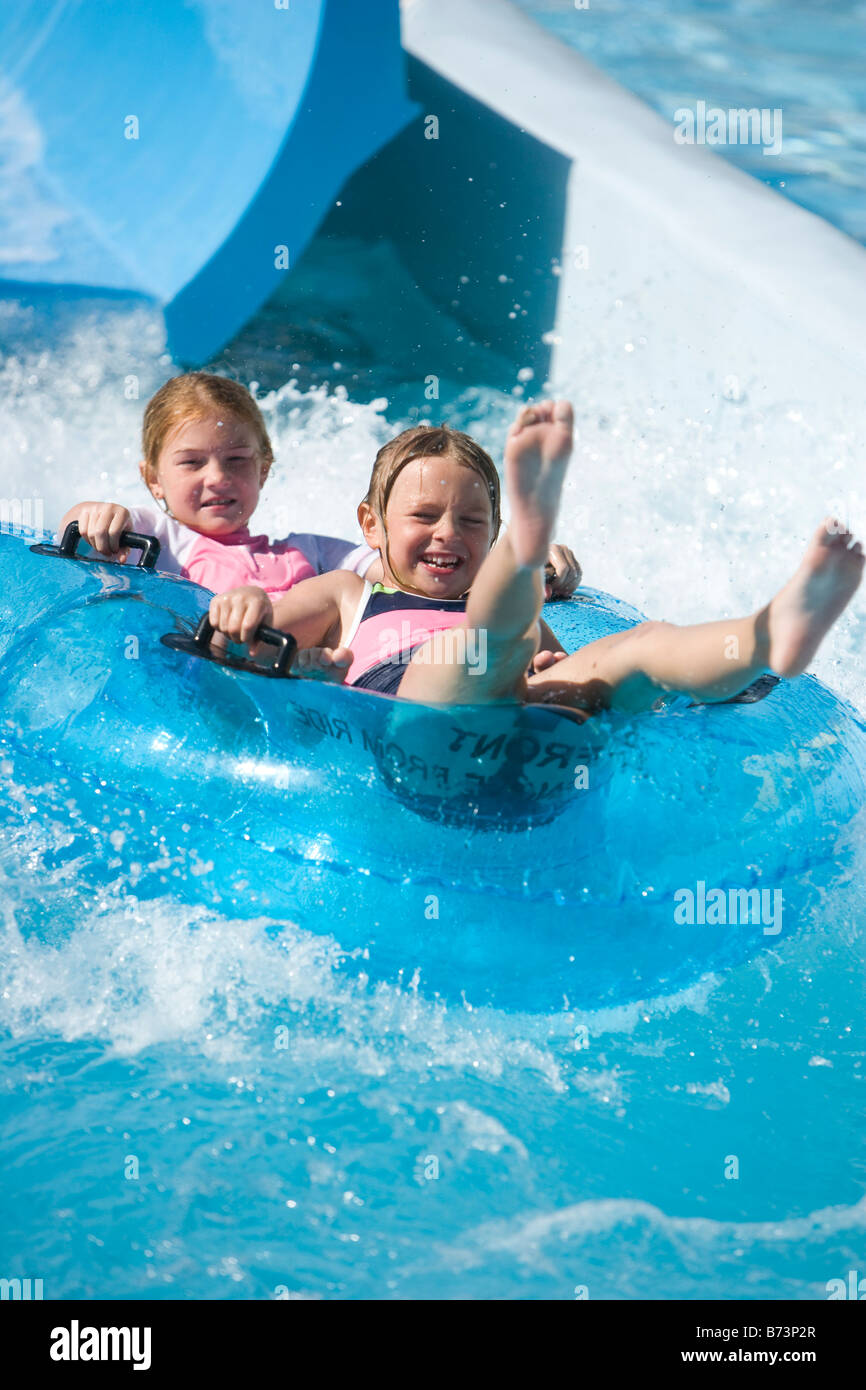 Portrait Of Girls Sliding Down Waterslide Together On Innertube In