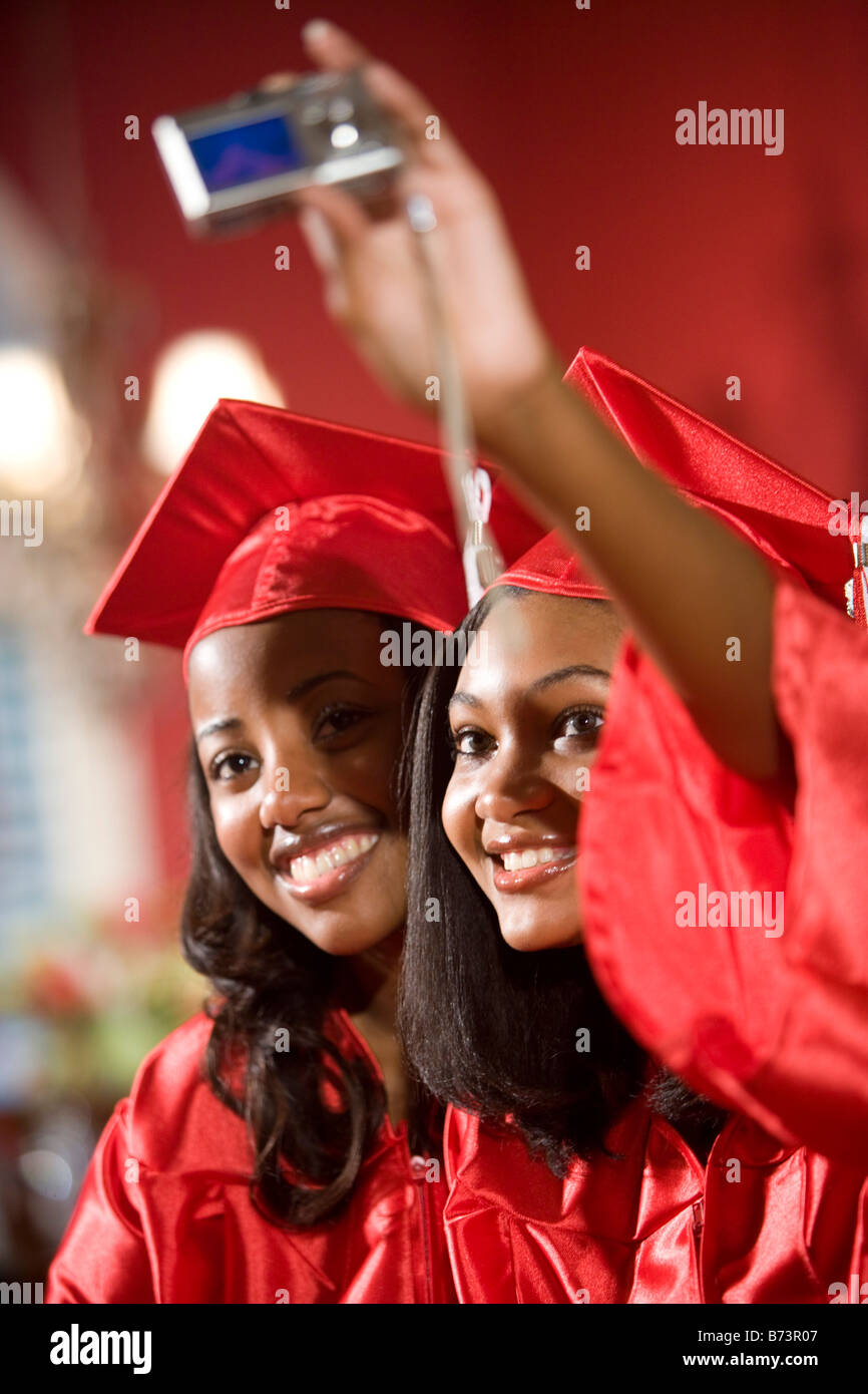 African American girls in graduation cap and gown photographing ...