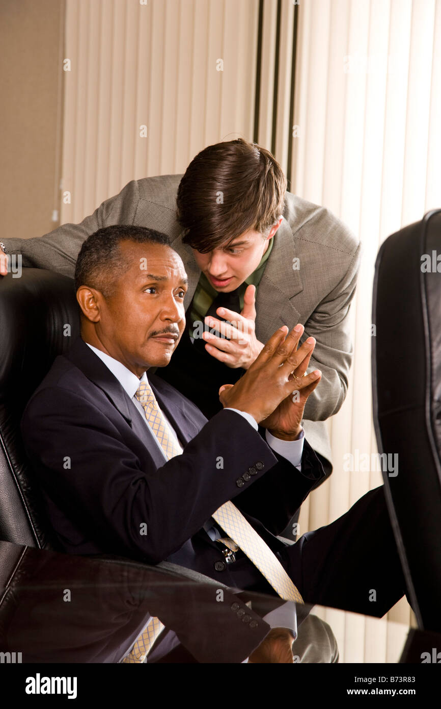 Young employee whispering to African-American executive in conference ...