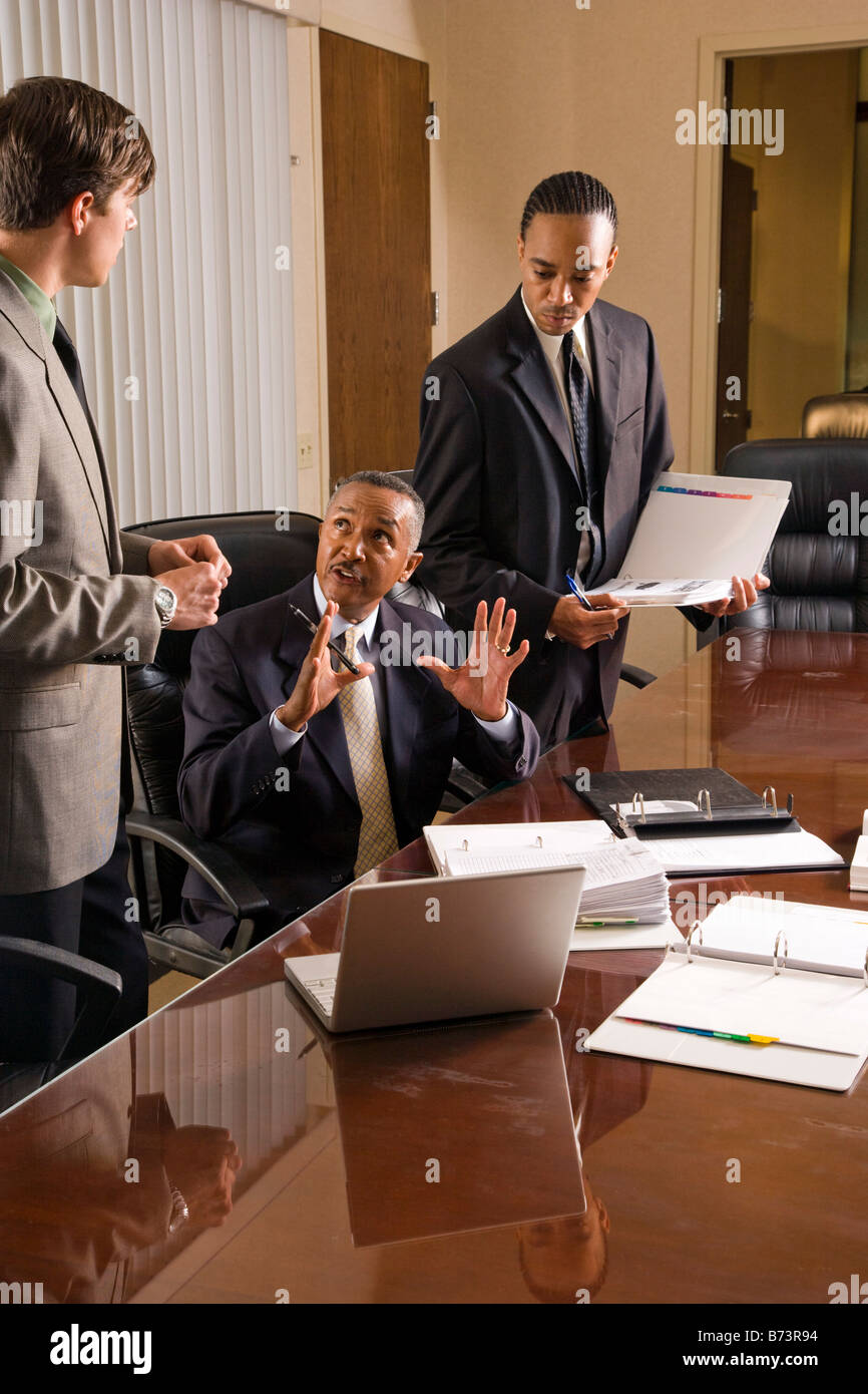 Employees assisting African-American executive reviewing paperwork ...