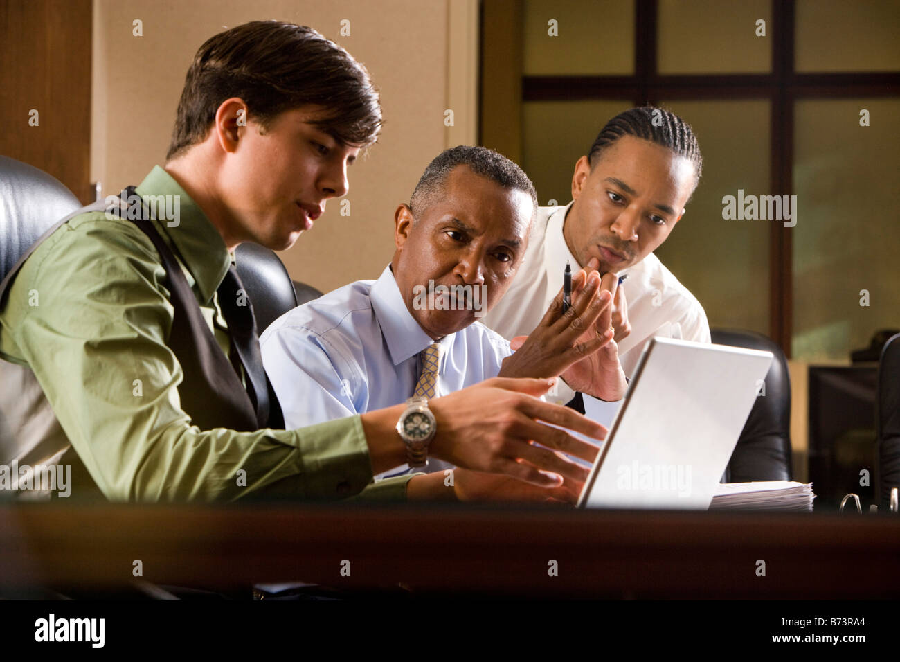 Employees assisting African-American executive reviewing paperwork ...