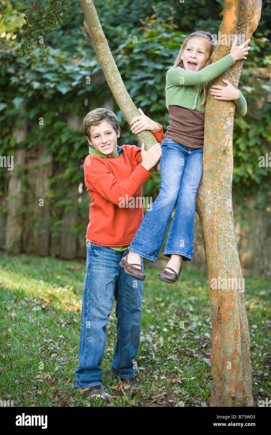 Two children climbing tree in backyard Stock Photo - Alamy