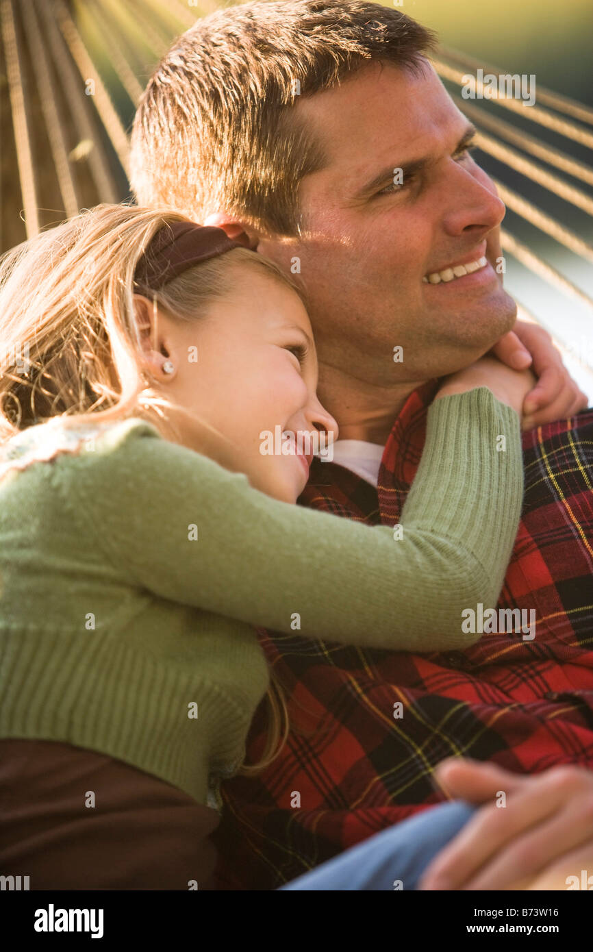 Portrait of father and daughter cuddling in hammock Stock Photo - Alamy
