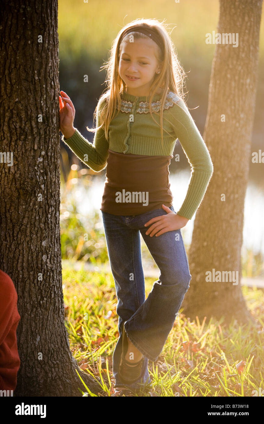 Young girl standing beside tree outdoors Stock Photo - Alamy