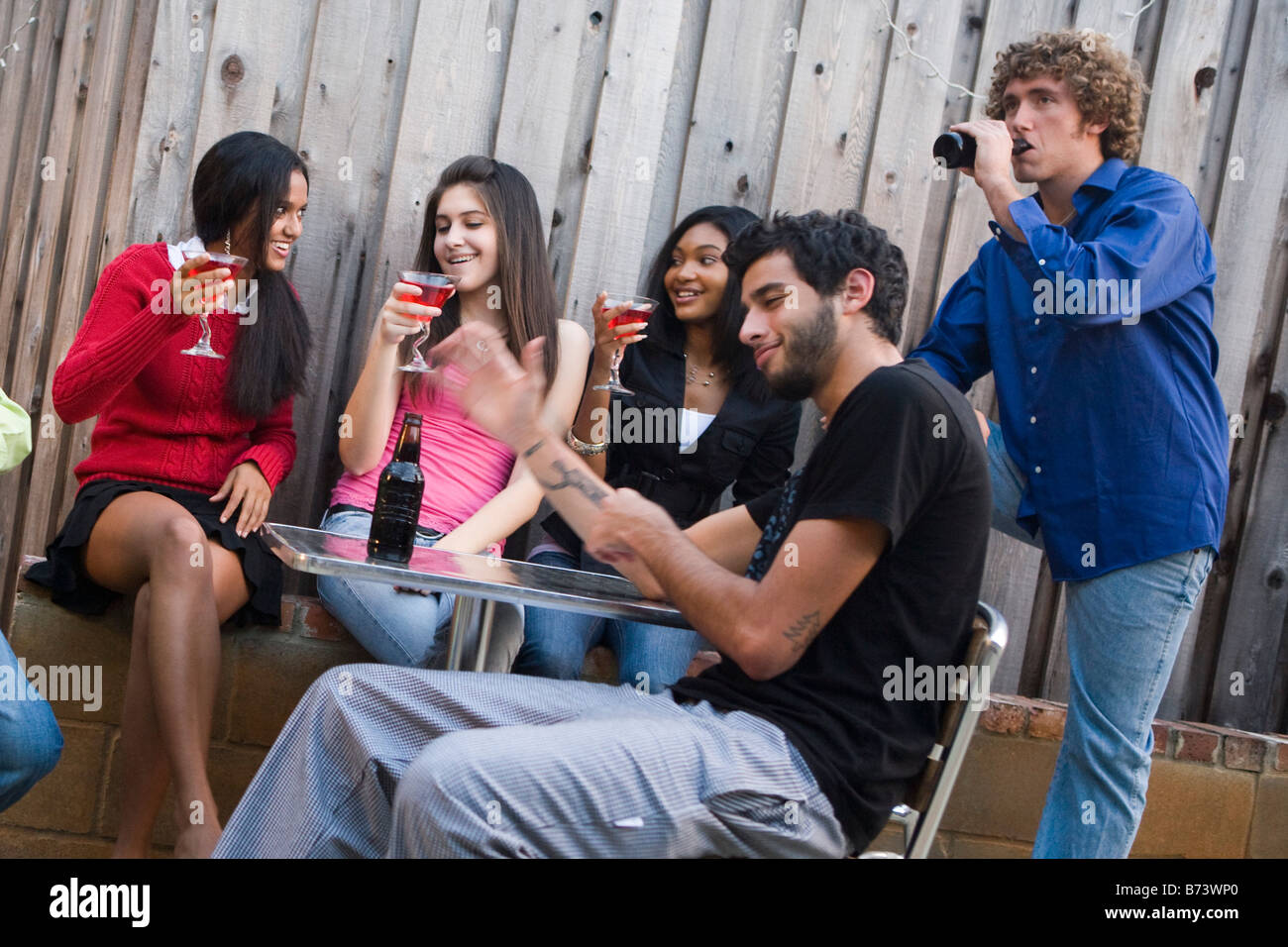 Multi-ethnic friends socializing and having drinks on outdoor patio ...