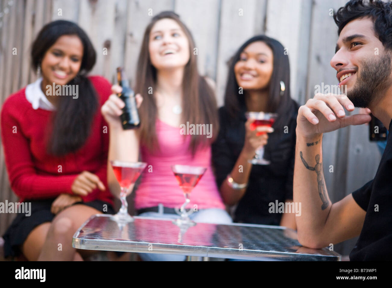 Multi-ethnic friends socializing and having drinks on outdoor patio ...