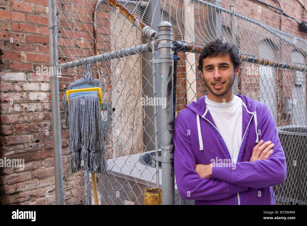 Young man standing next to chain-link fence in alleyway Stock Photo - Alamy